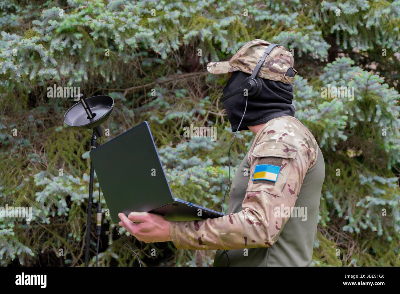 A military man in camouflage with a Ukrainian flag uses a directional ...