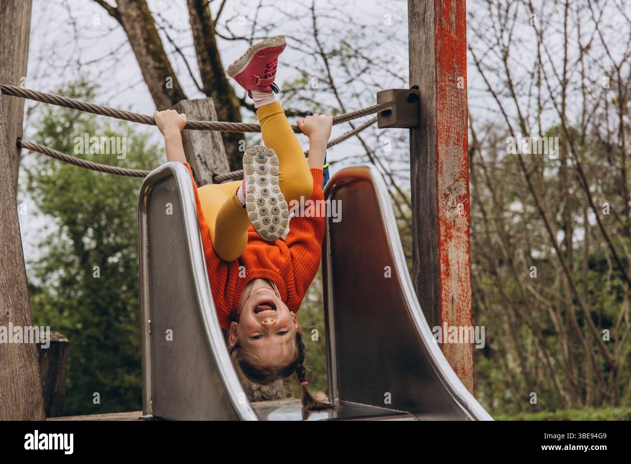 Child sliding down a playground slide with a big smile, enjoying a ...