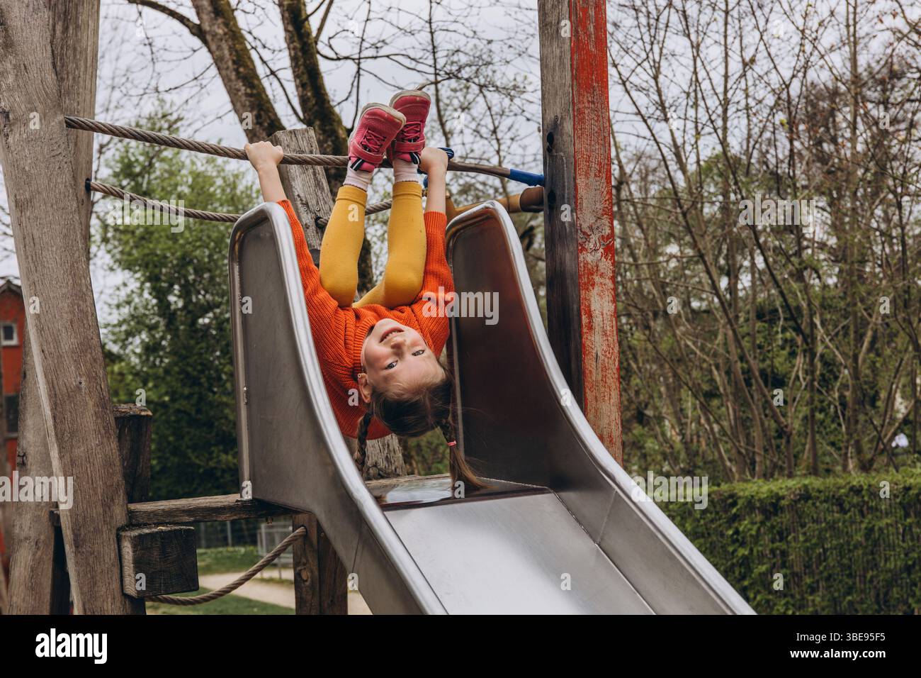 Child sliding down a playground slide with a big smile, enjoying a ...