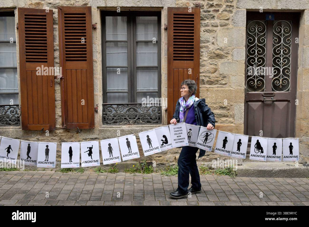 A woman holds a banner representing anonymous victims during a ...