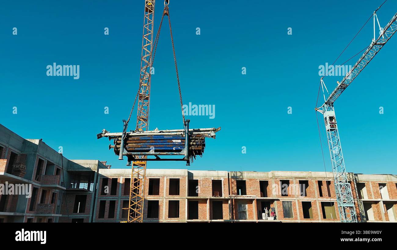 Tower crane lifting construction materials at a building site with ...