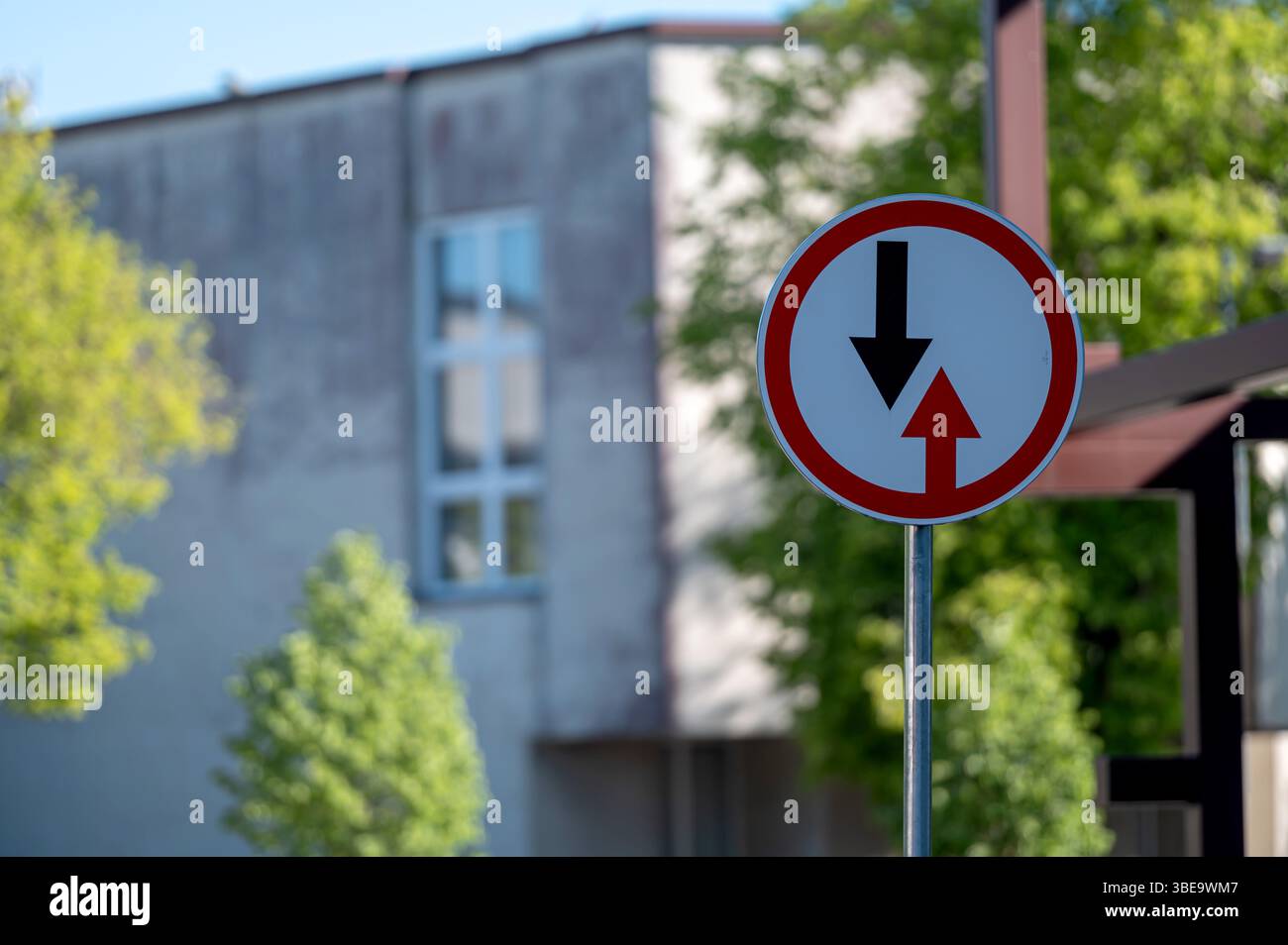 A traffic sign displays red and black arrows signaling alternating ...