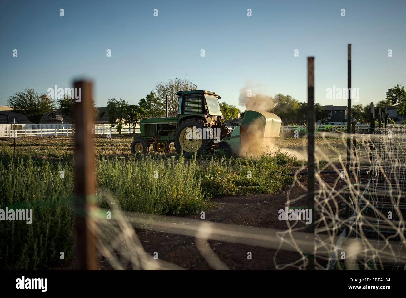 A tractor clears farmland in Agritopia, a community nestled around a ...