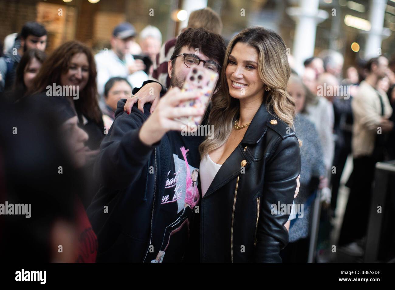 Delta Goodrem takes photos with fans, as she surprises commuters with a ...