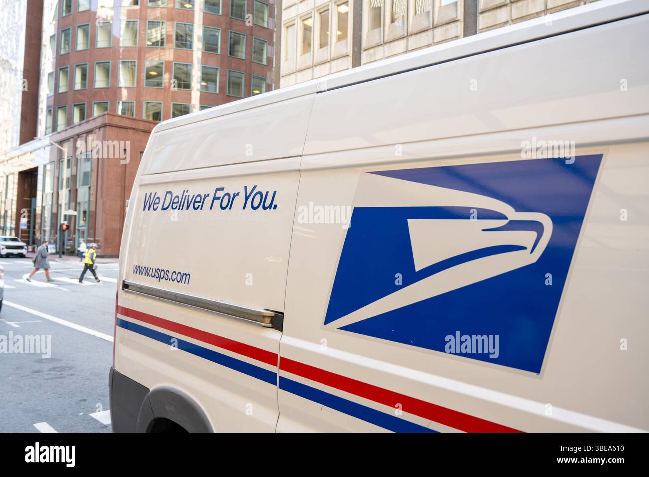 Close-up of USPS delivery van with red, white, and blue logo and 'We ...
