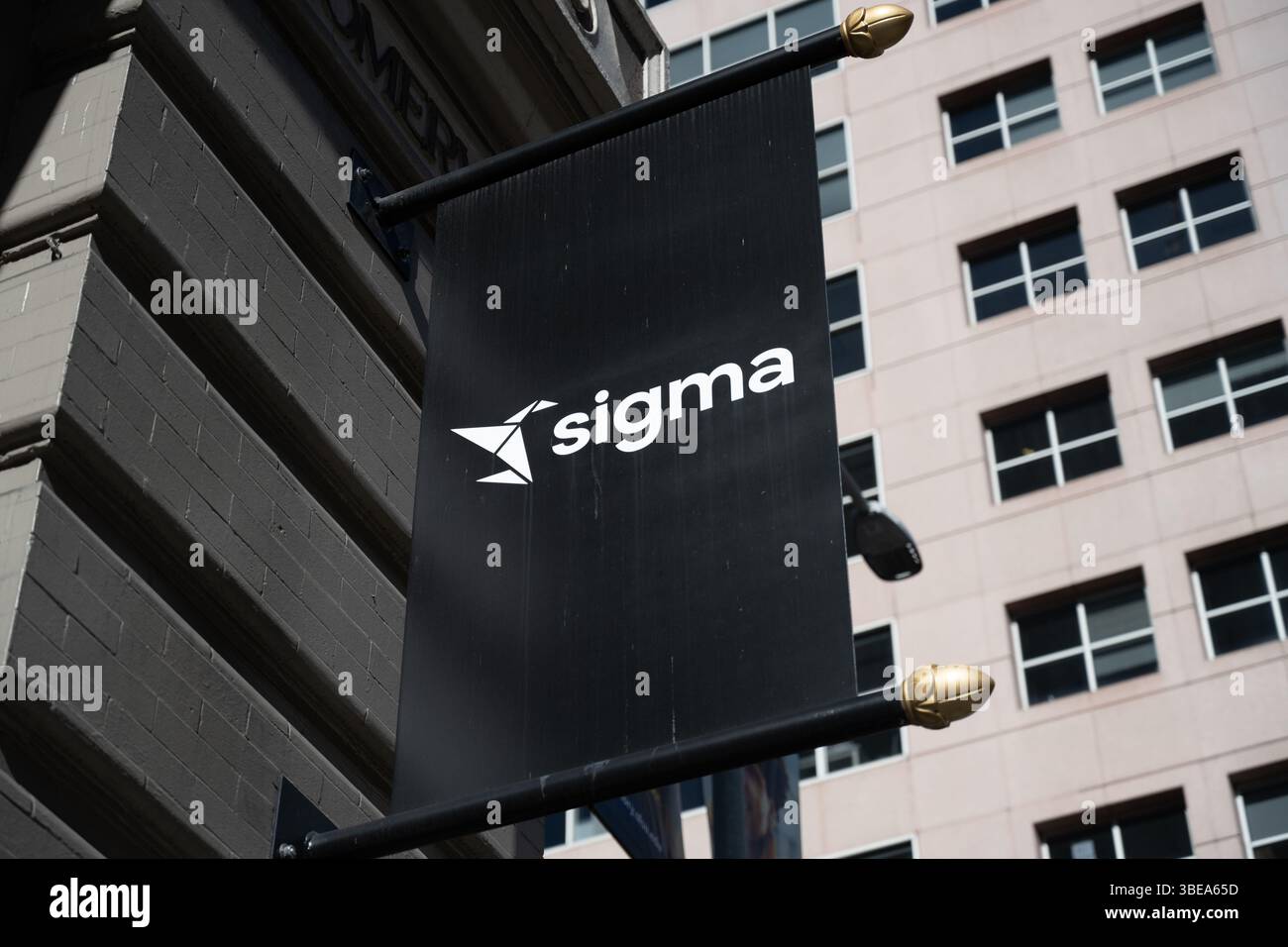 Black banner with white Sigma Computing logo mounted on a gray building ...