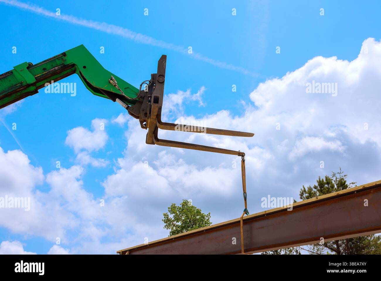 Heavy machinery telehandler supports steel beam against construction ...