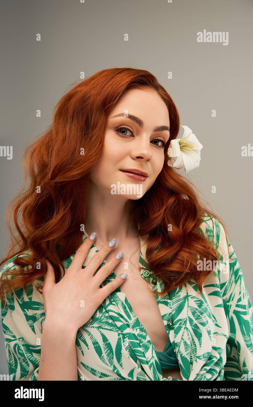 A beautiful woman poses confidently with wavy red hair adorned with a ...