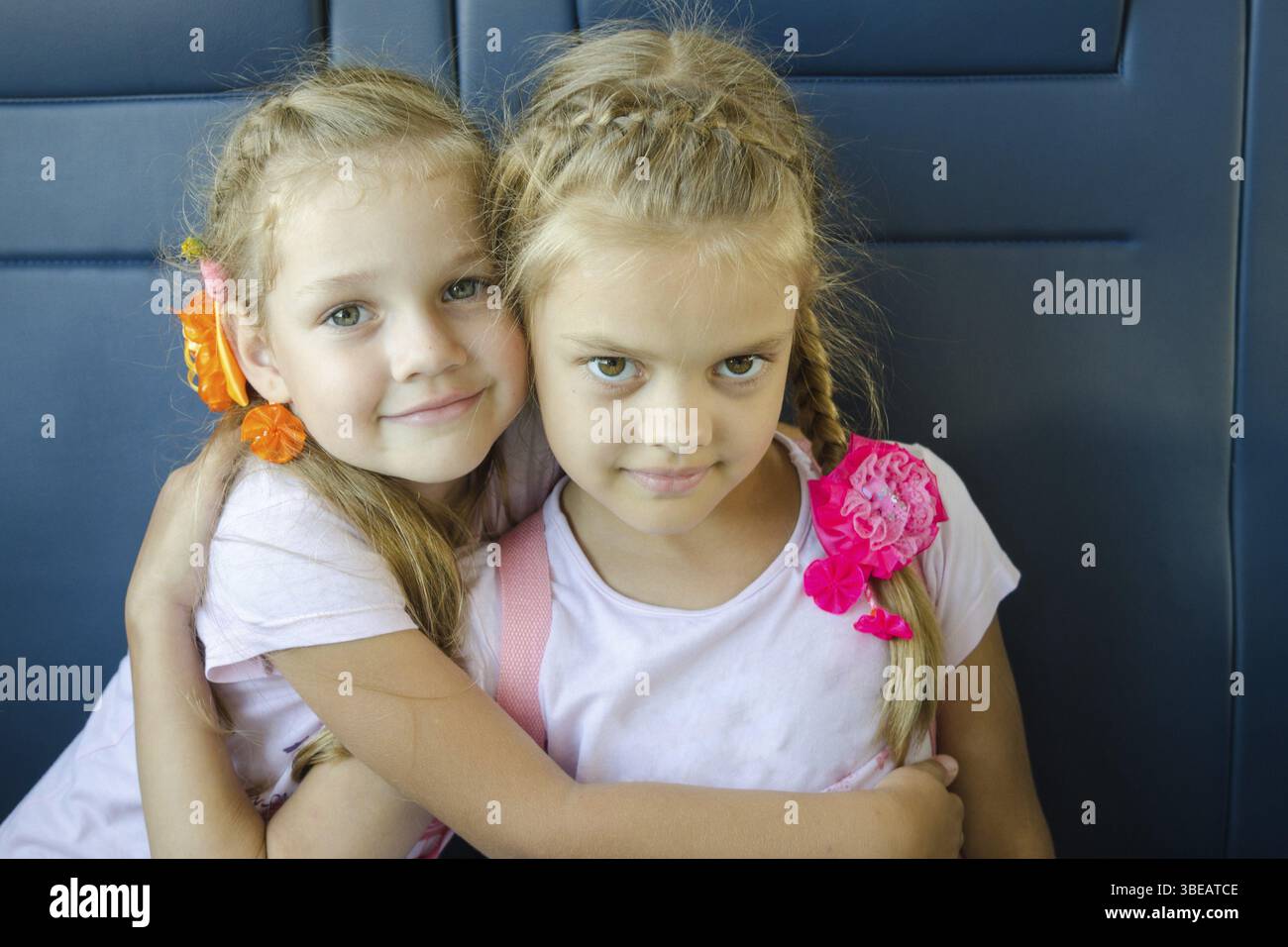 Two girls hugging look in the frame, sitting in an electric train ...