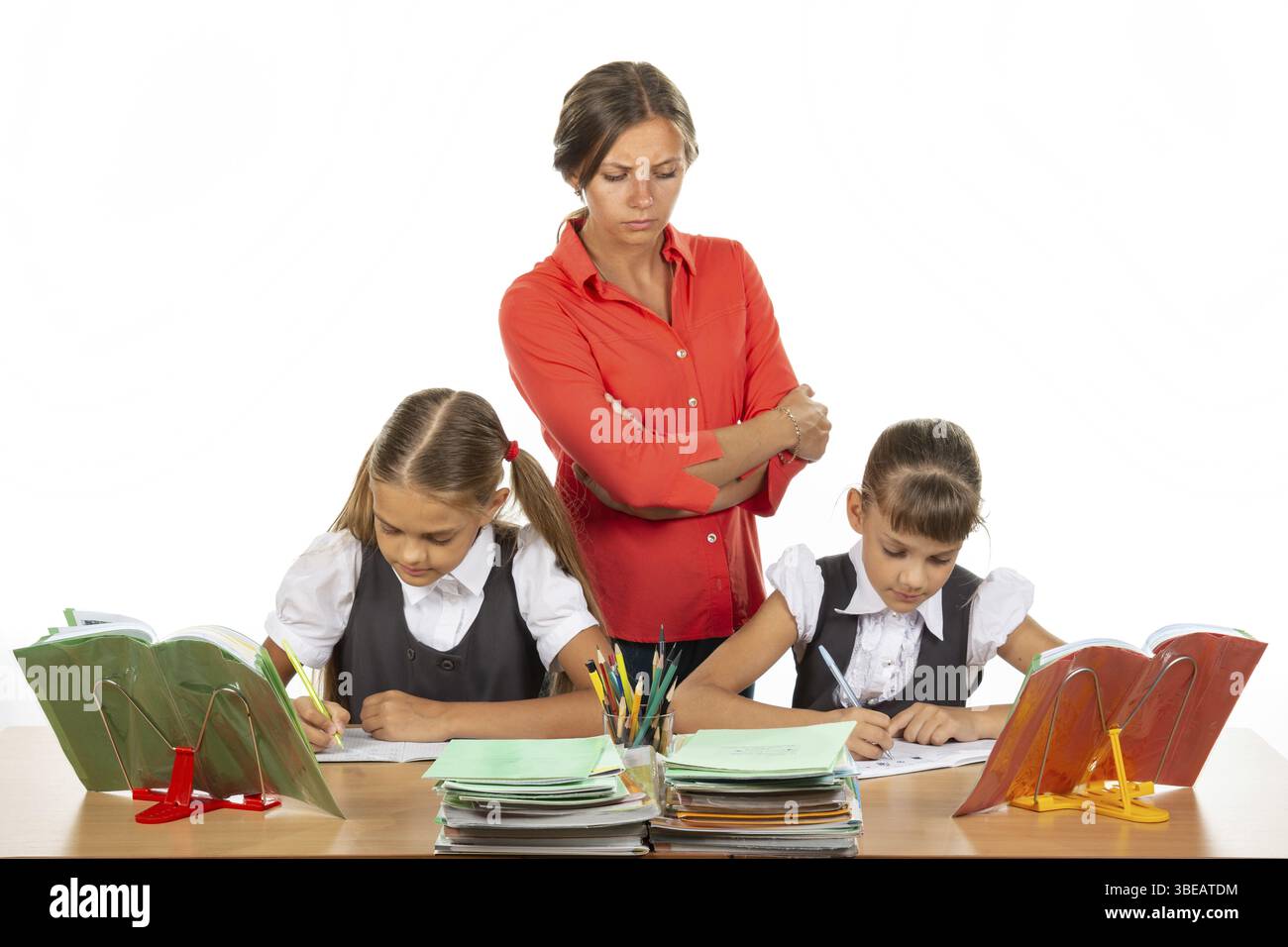 A strict teacher stands above the children who solve the task Stock ...
