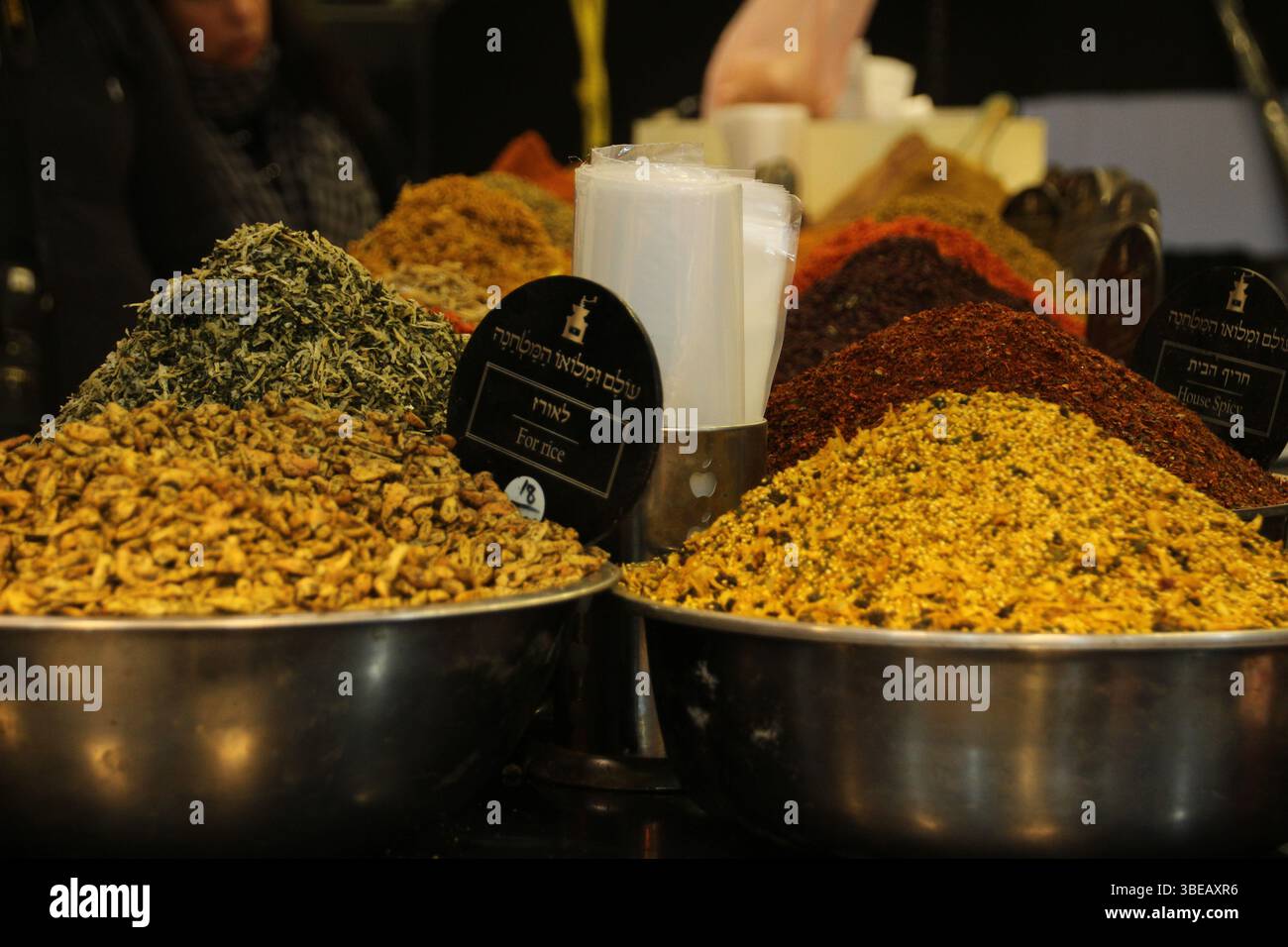 Various types of spices displayed in large metal bowls, neatly ...