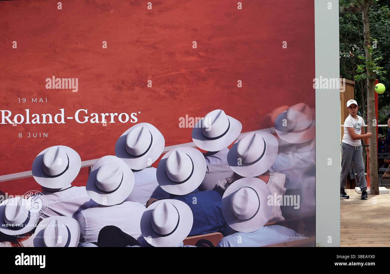 A child plays with a giant tennis ball next to a Roland Garros poster ...