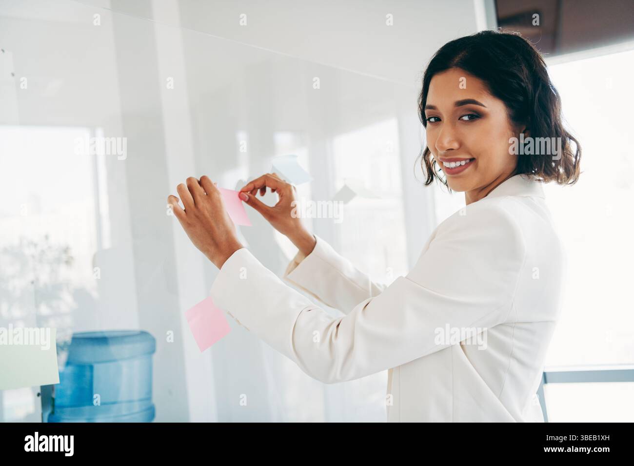Confident businesswoman organizing sticky notes in an office workspace ...