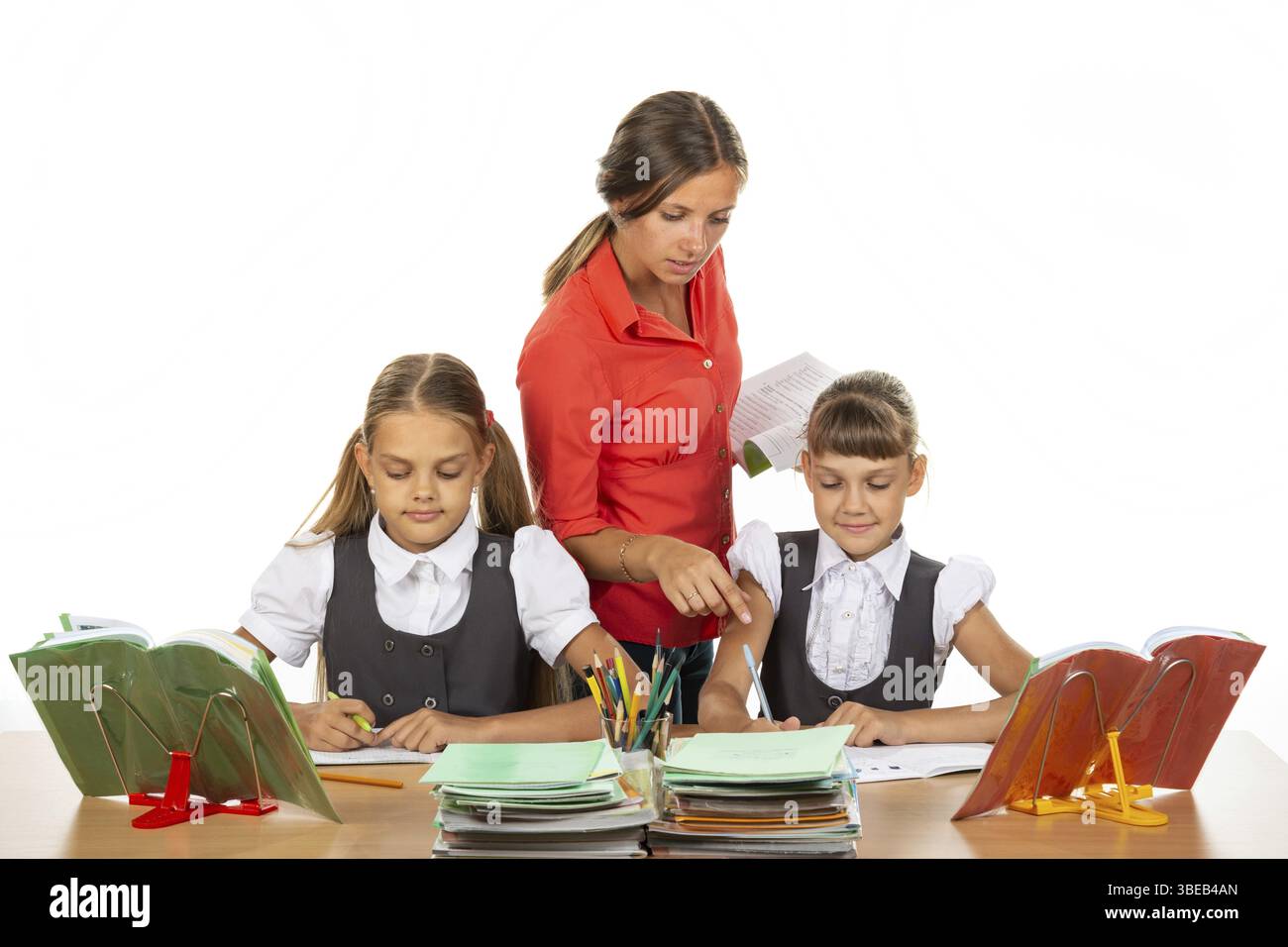 The teacher helps schoolgirls in the lesson, prompting how to solve the ...