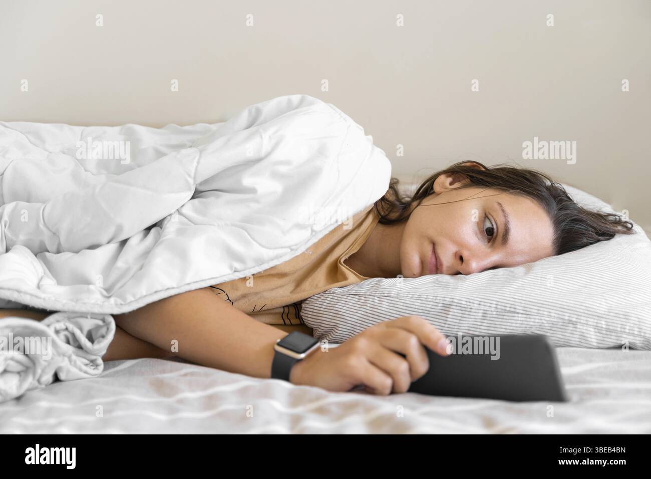 Young woman goes to sleep Phone addiction, insomnia. try to fall asleep ...