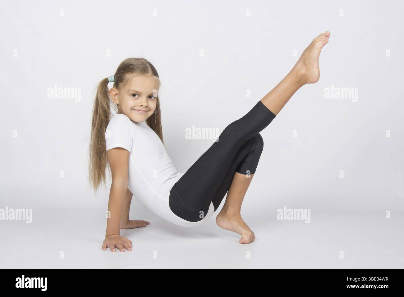 An aspiring gymnast pulls his right leg resting on the hands and ...