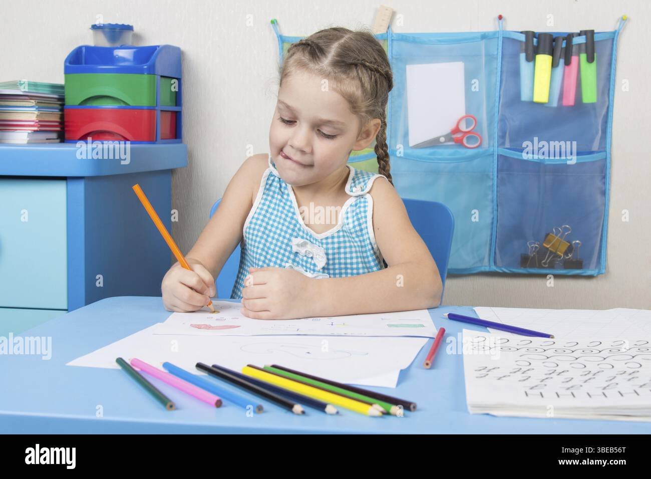Five-year girl stuck out her tongue with pleasure, drawing picture at ...