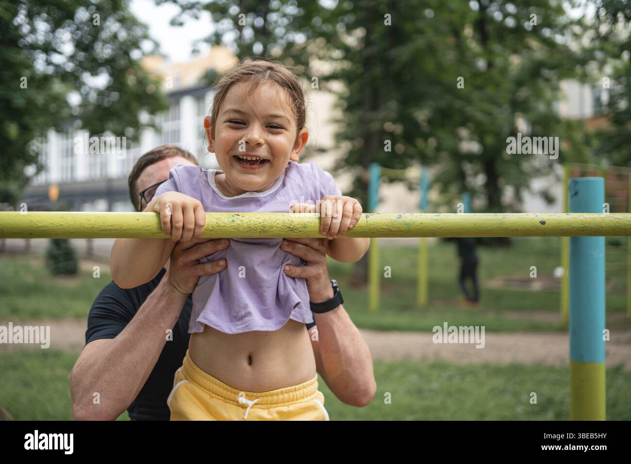 Father with child girl doing pull-ups on workout outdoor area. Healthy ...
