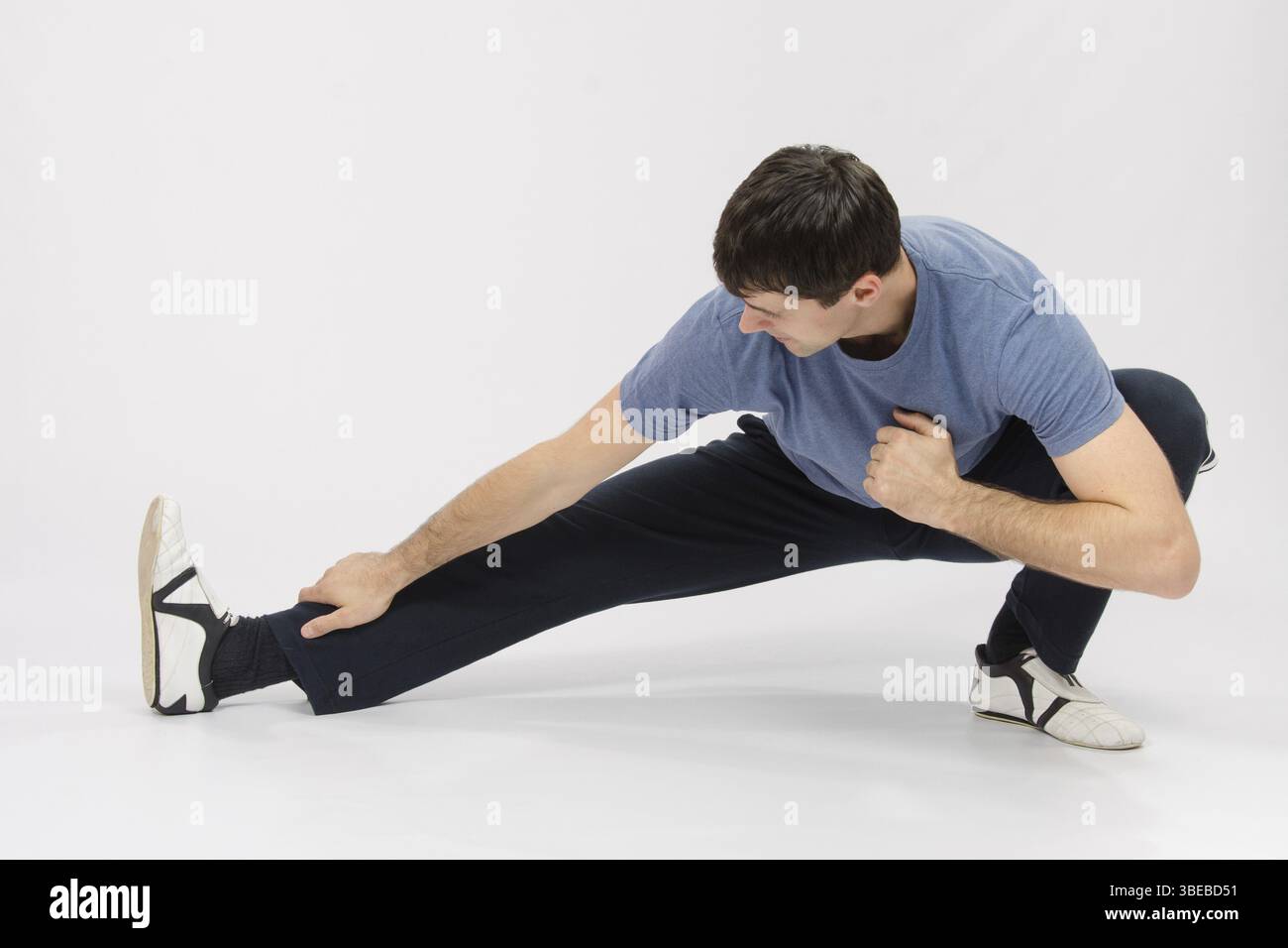 Athlete crouching pulling muscles of the right leg Stock Photo - Alamy