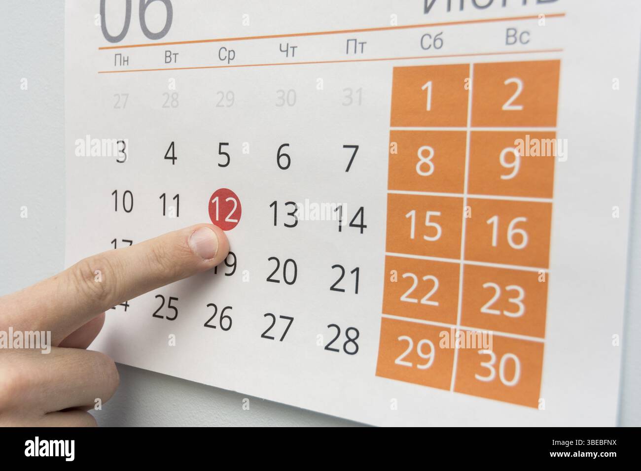Finger points to a holiday in the wall calendar Stock Photo - Alamy