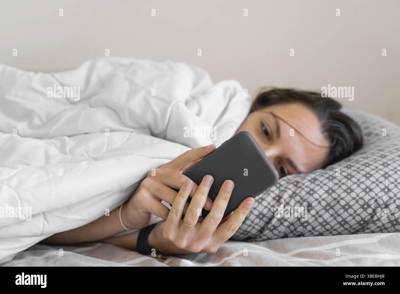 Young woman goes to sleep Phone addiction, insomnia. try to fall asleep ...