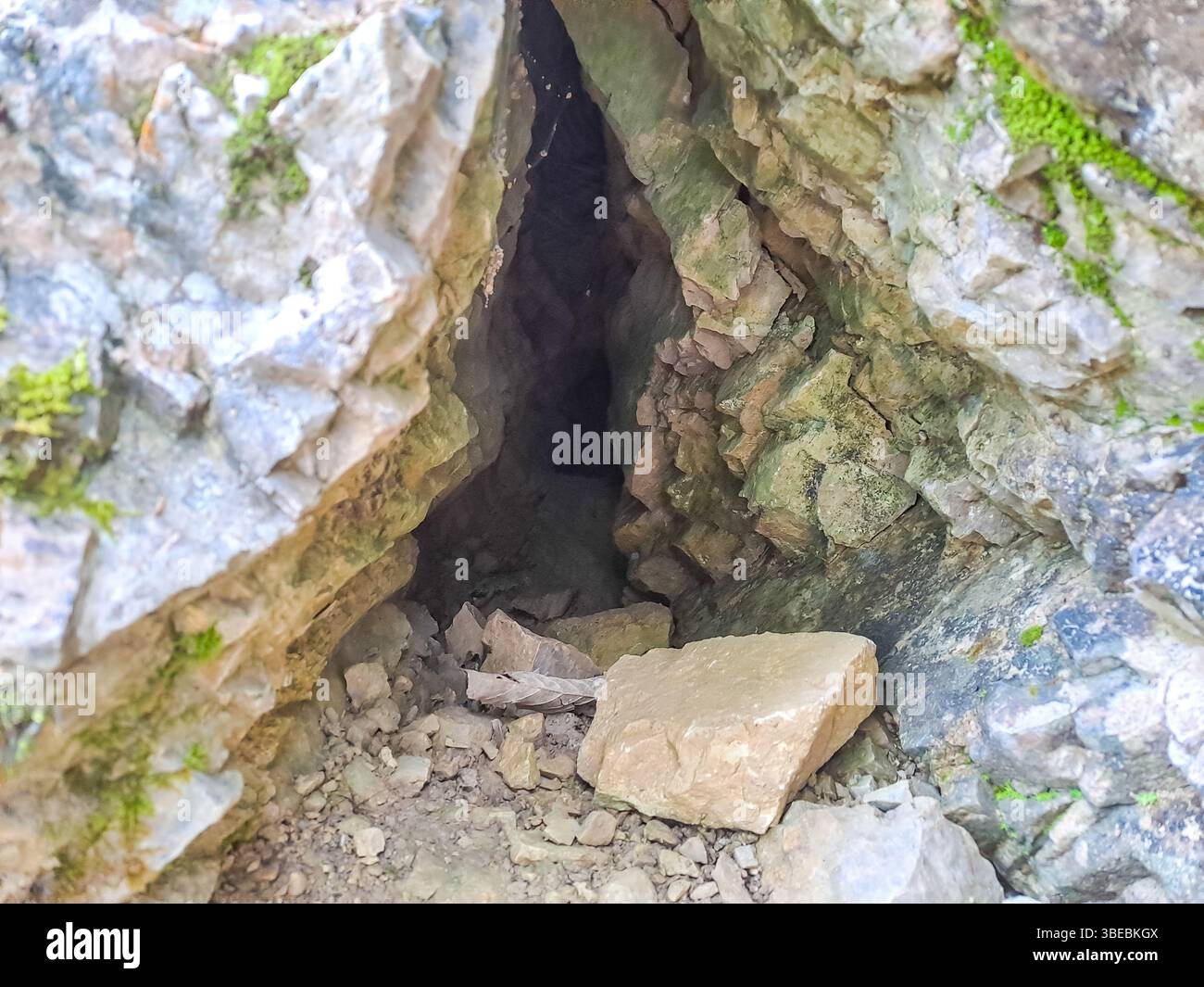 A small cave entrance nestled among rocks in the Alps, Switzerland ...