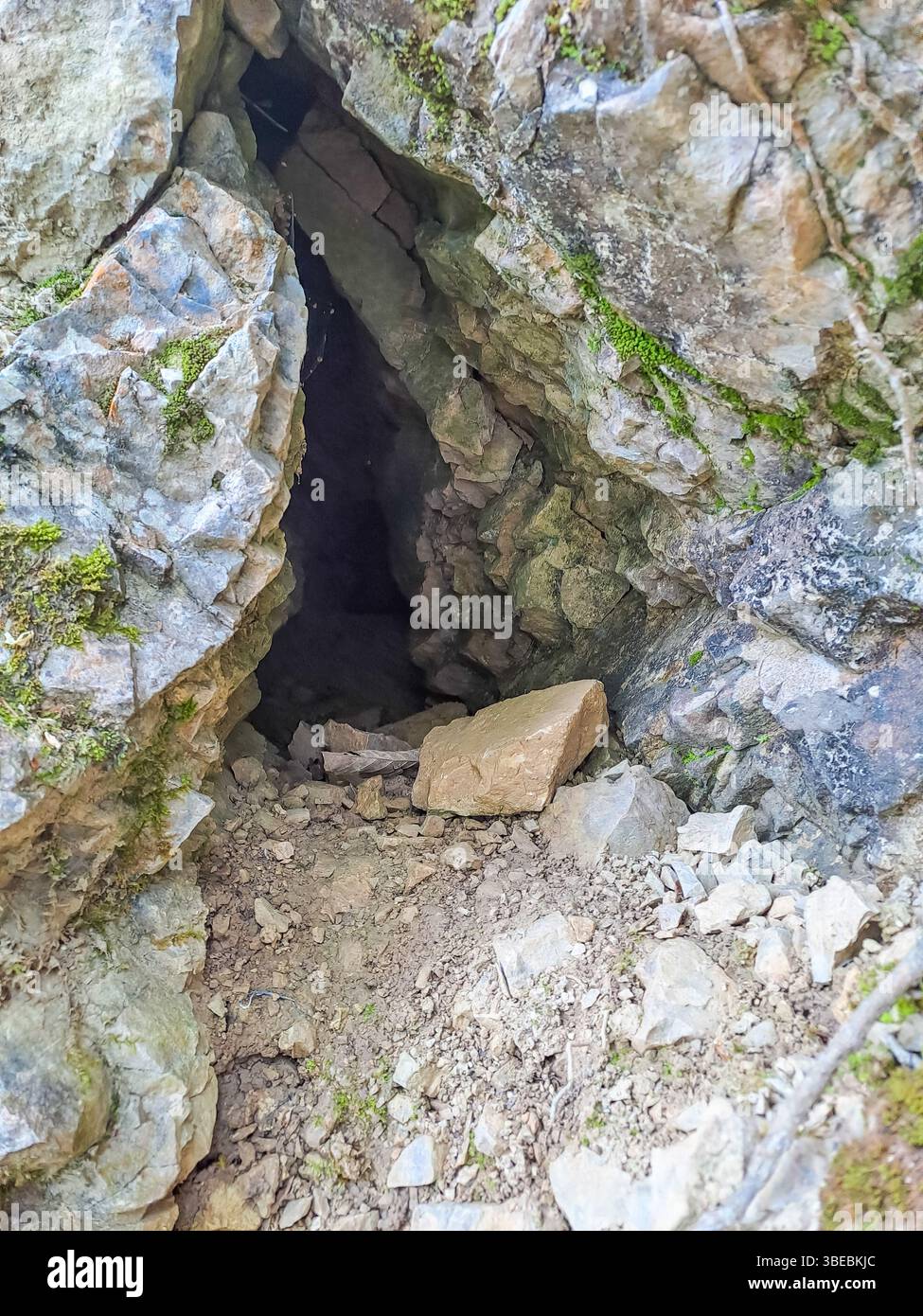 A small cave entrance nestled among rocks in the Alps, Switzerland ...