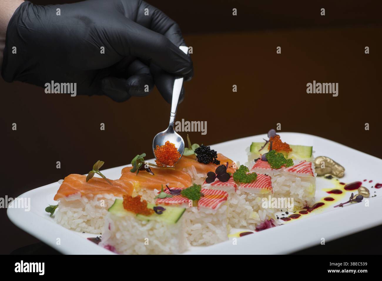 Chef decorates sushi with caviar. process of cooking sushi Stock Photo ...