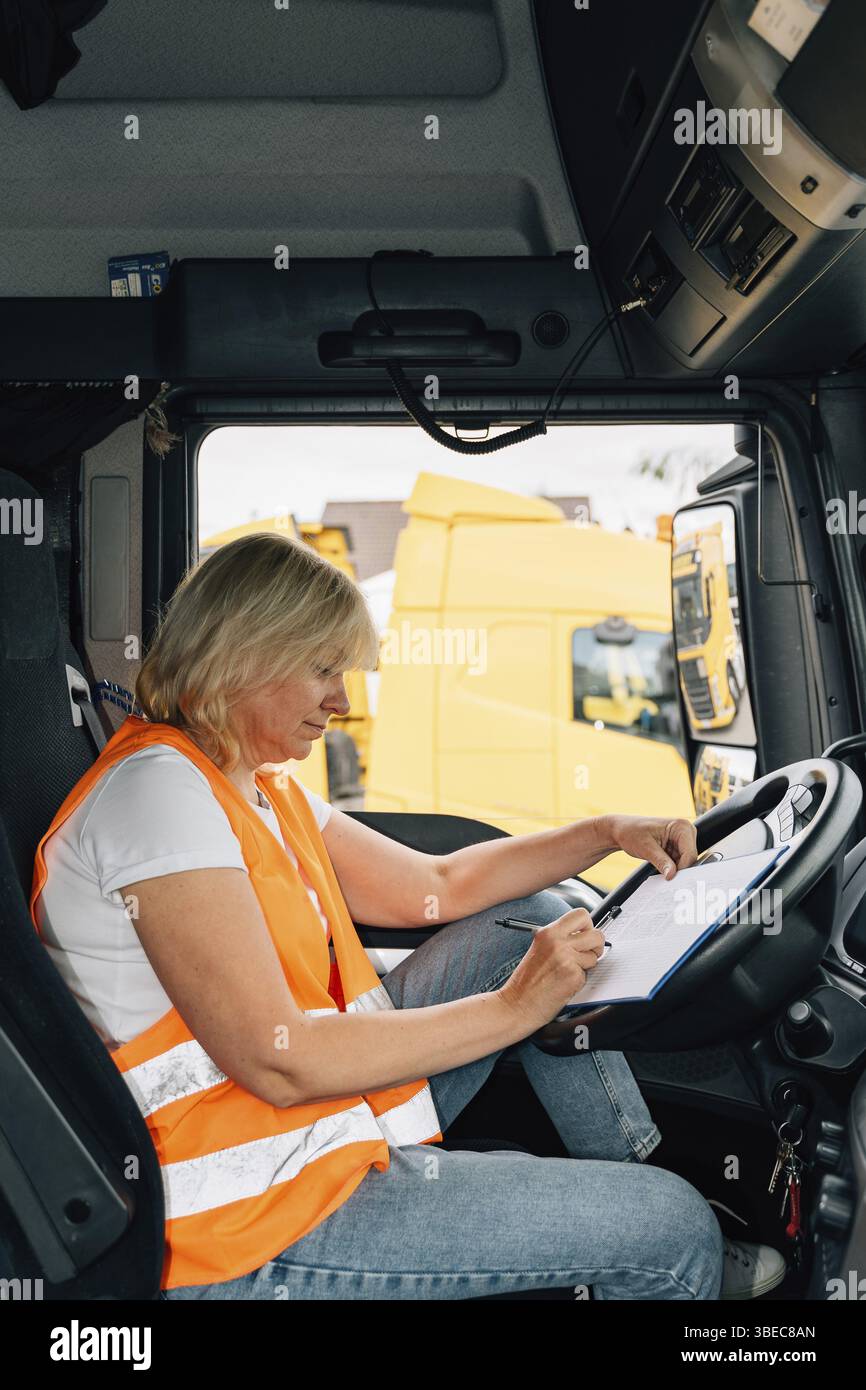 Mature woman truck driver steering wheel inside lorry cabin. Happy ...