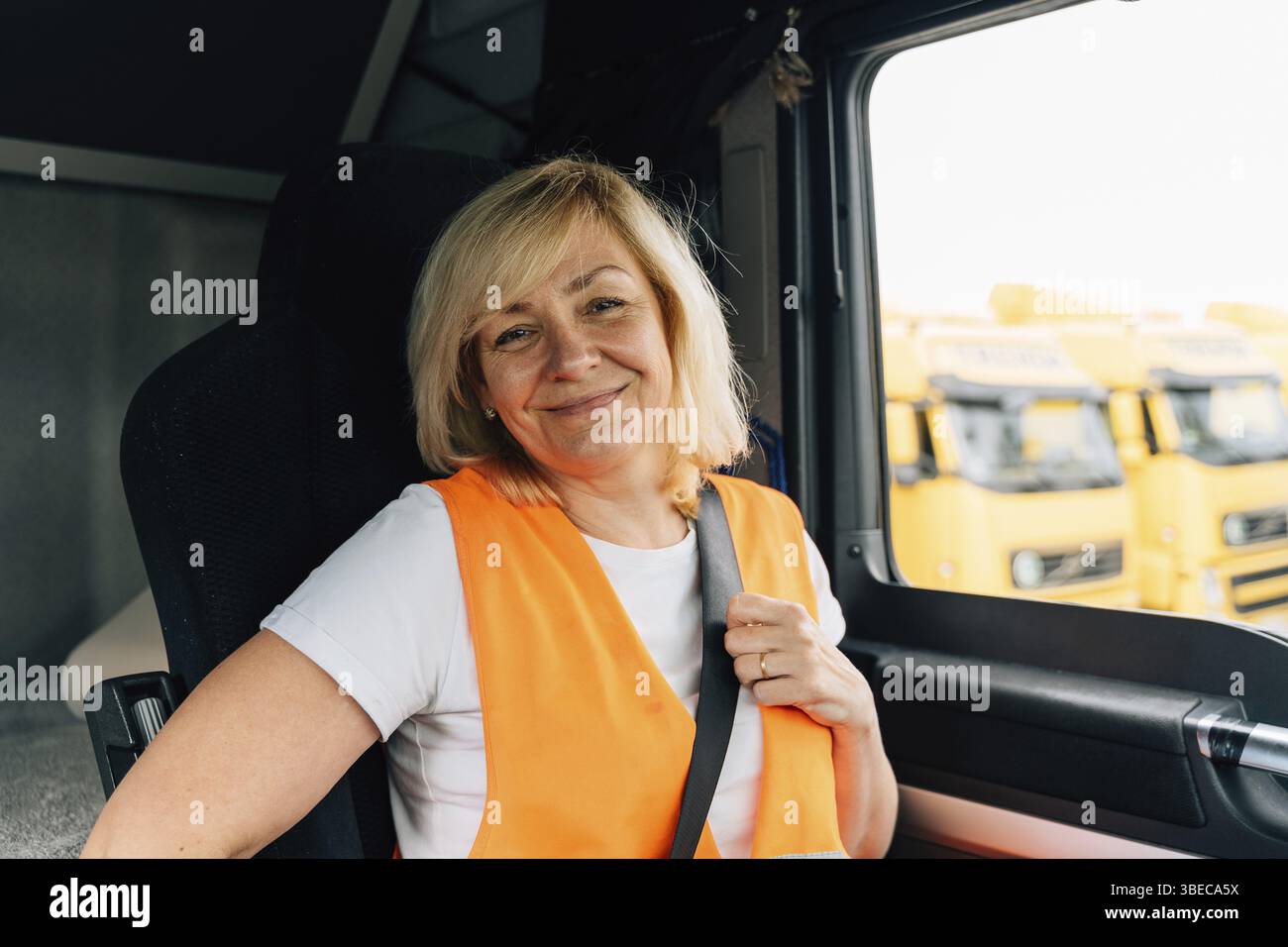 Mature woman truck driver steering wheel inside lorry cabin. Happy ...