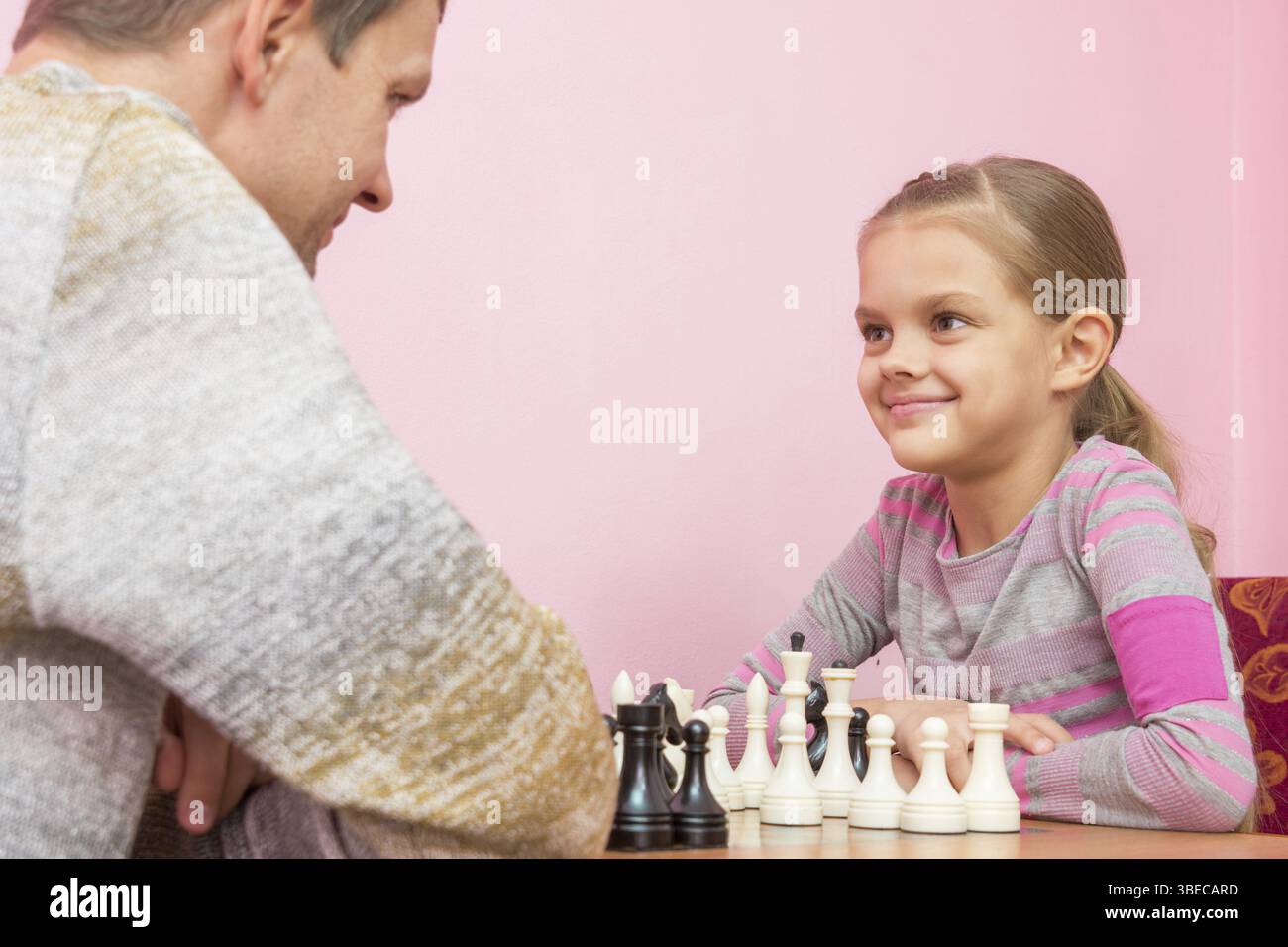 Dad and daughter happily look at each other, playing chess Stock Photo ...