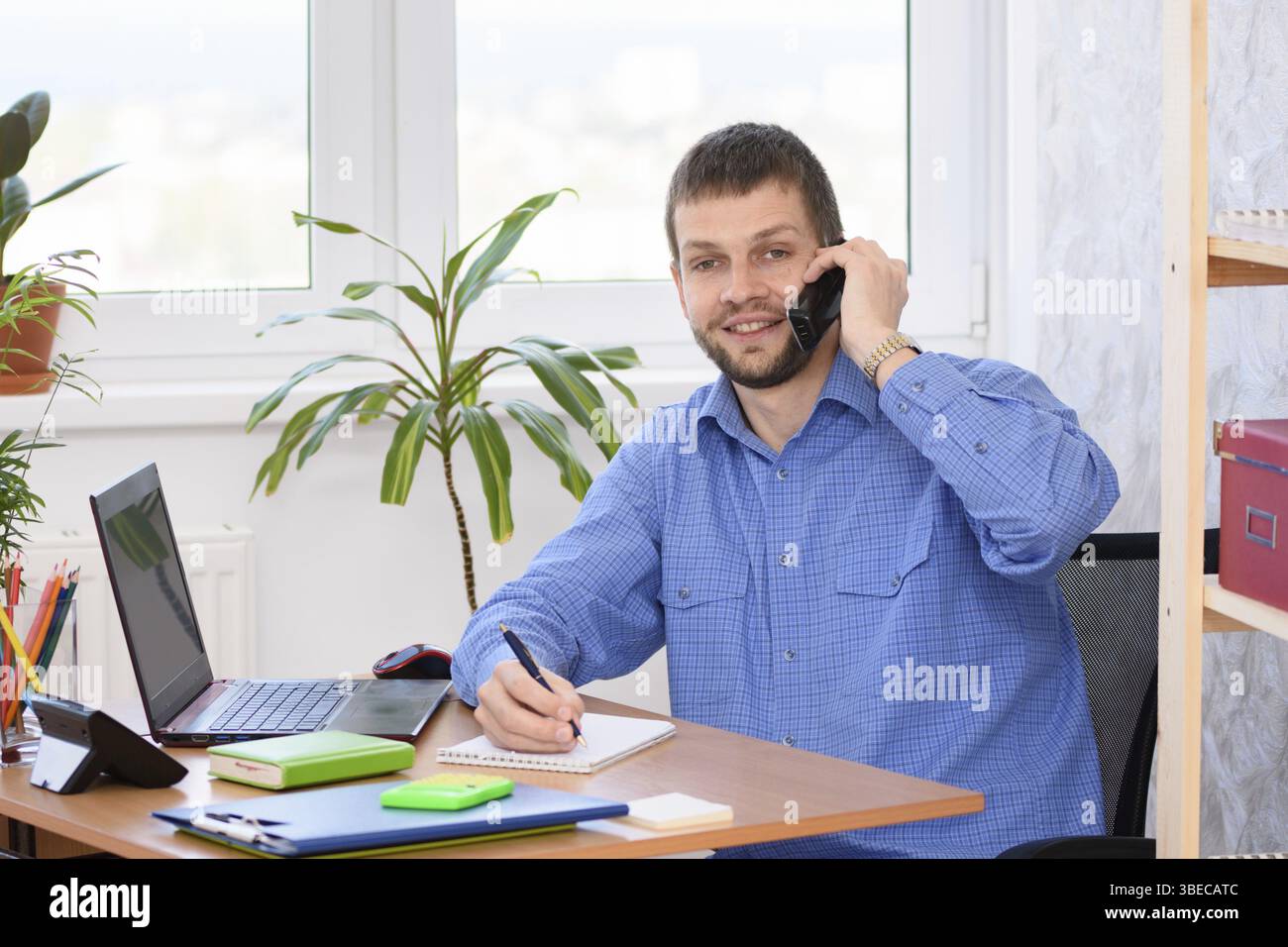 An office employee is talking on the phone with a smile and looked in ...