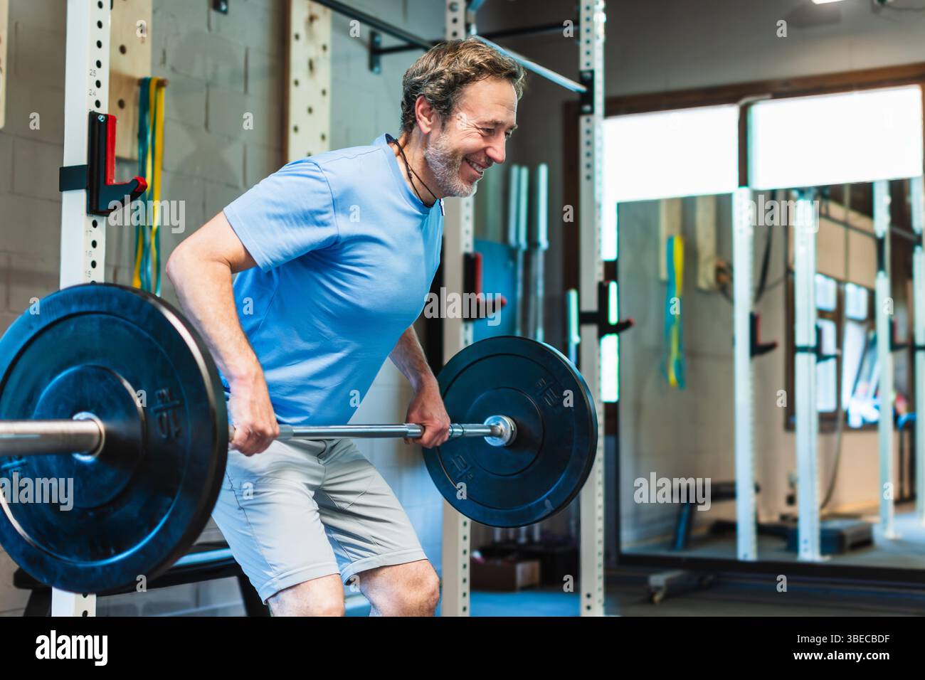 A man lifts an Olympic barbell with discs in a gym He is doing the back ...