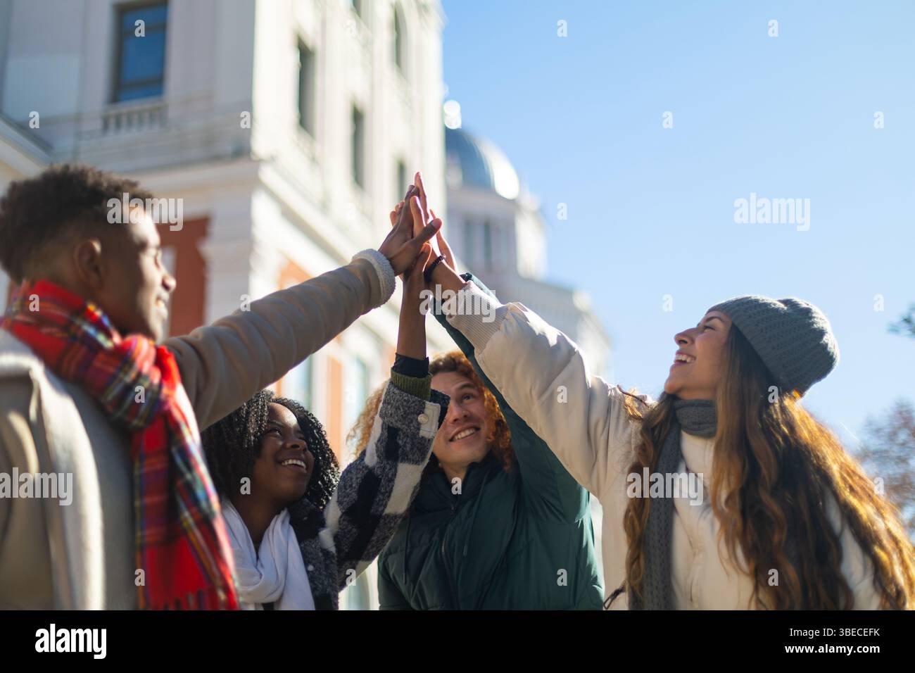 Four cheerful students joining hands together, celebrating their ...