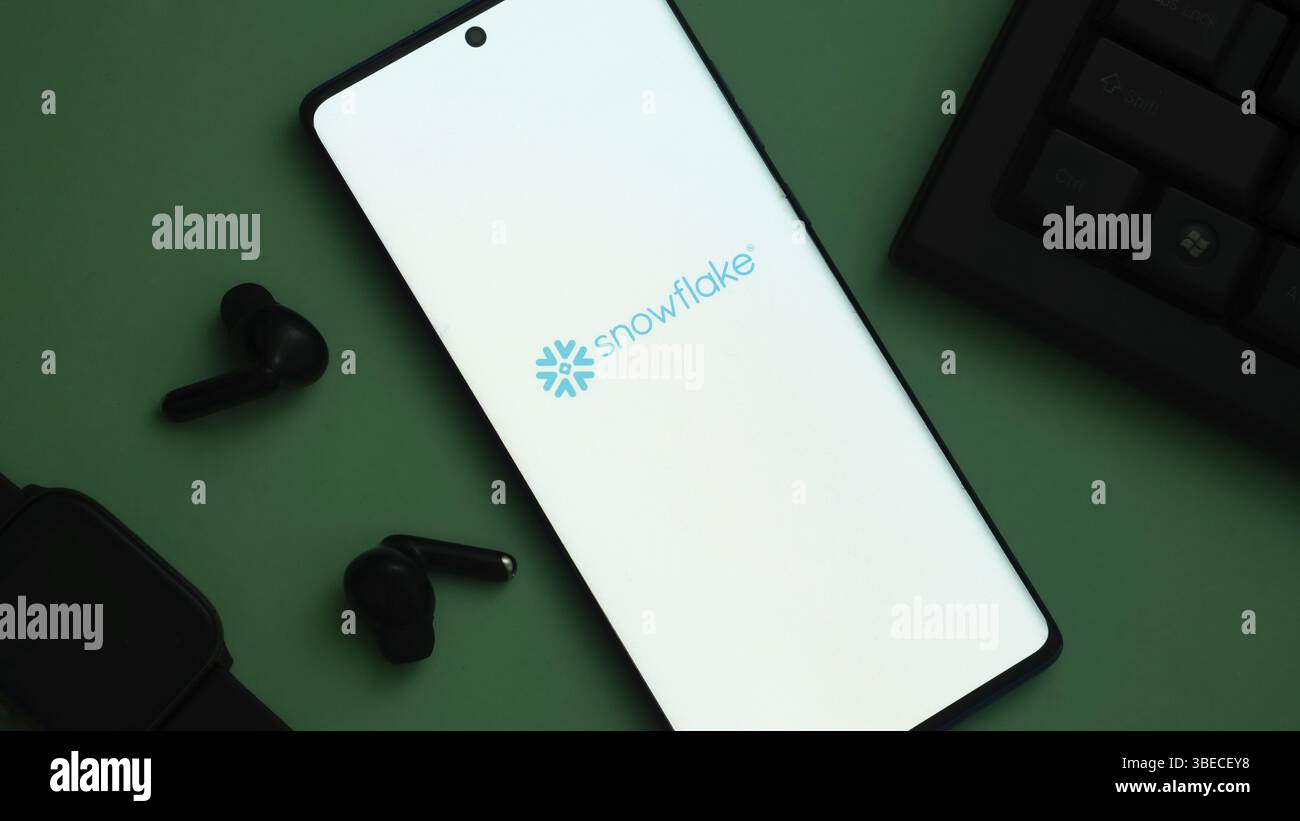 Snowflake logo on smartphone with white screen beside black earbuds and ...