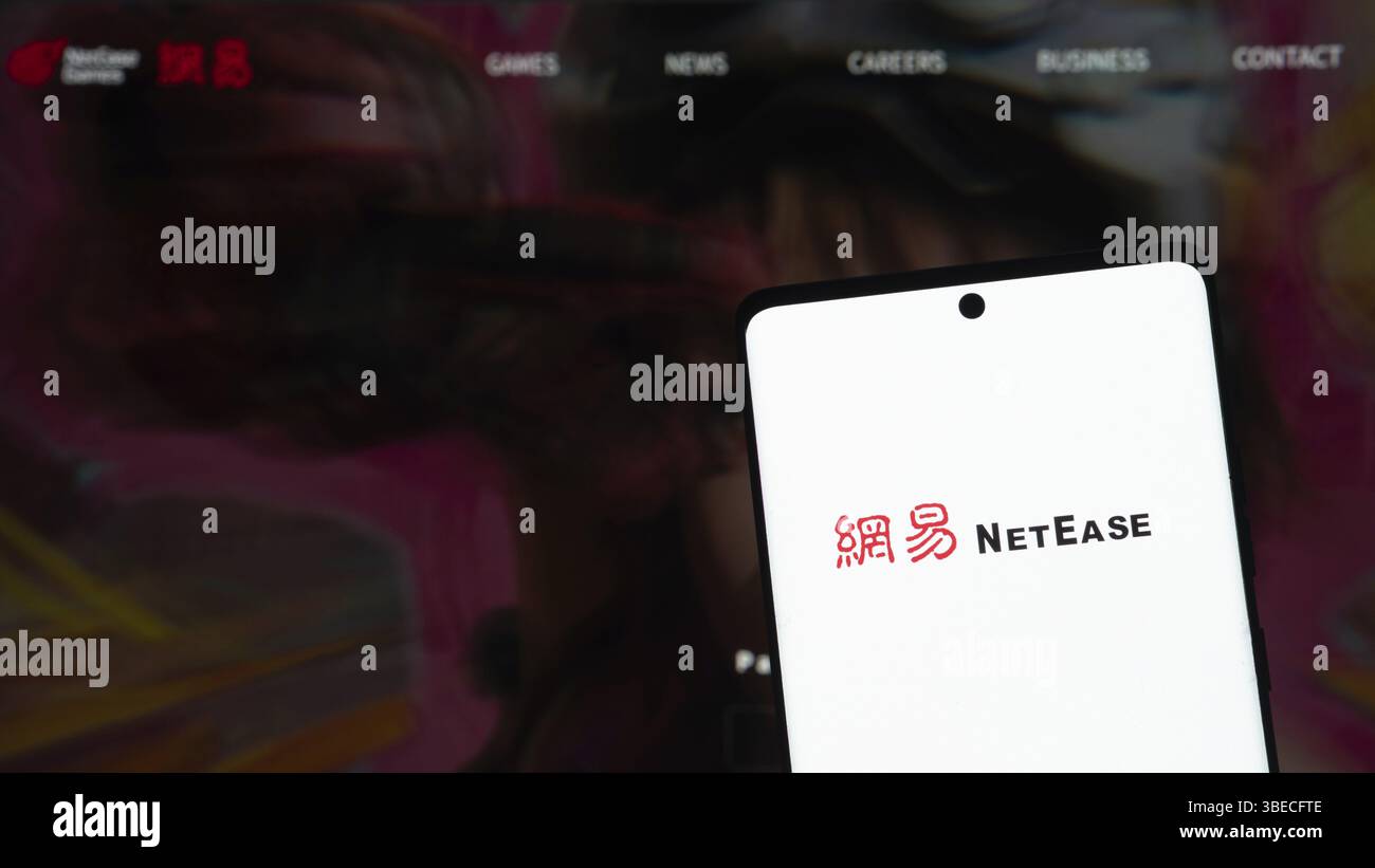 Netease logo appears on a smartphone against a blurred gaming portal background Stock Photo - Alamy