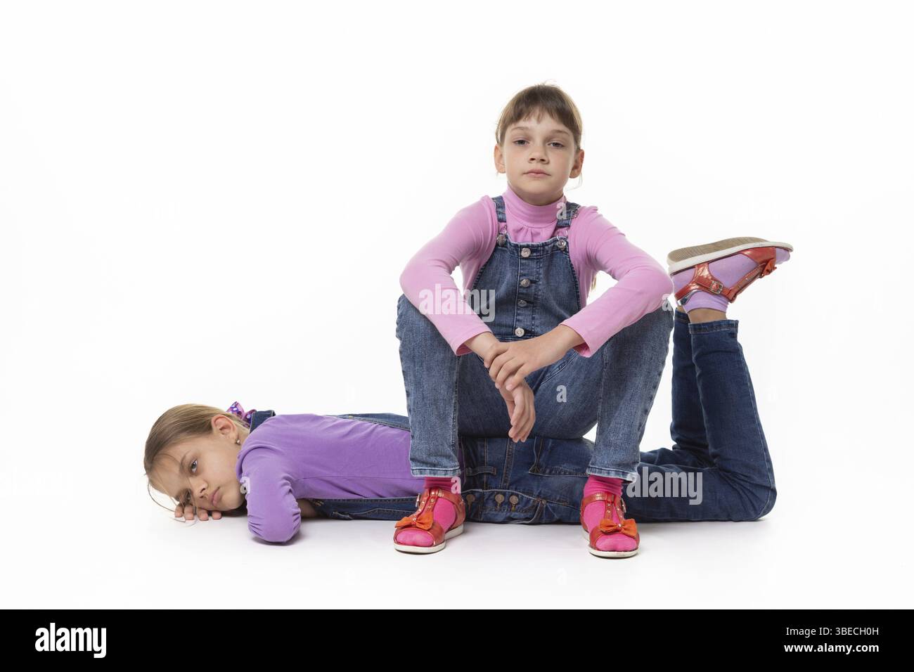 Two sad girls rest sitting and lying on a white background Stock Photo ...