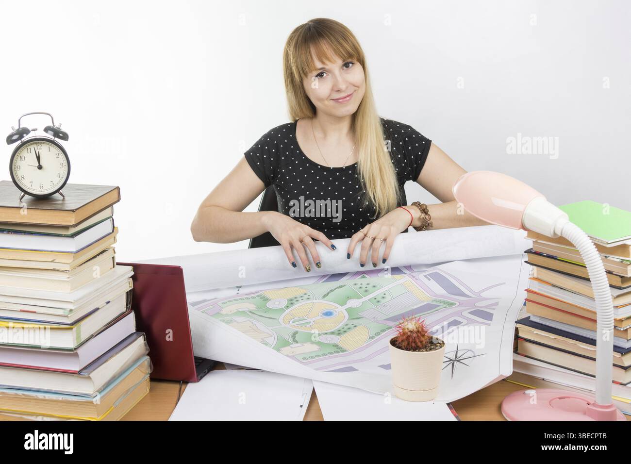 Girl design student at his desk with a smile turns to roll the finished ...