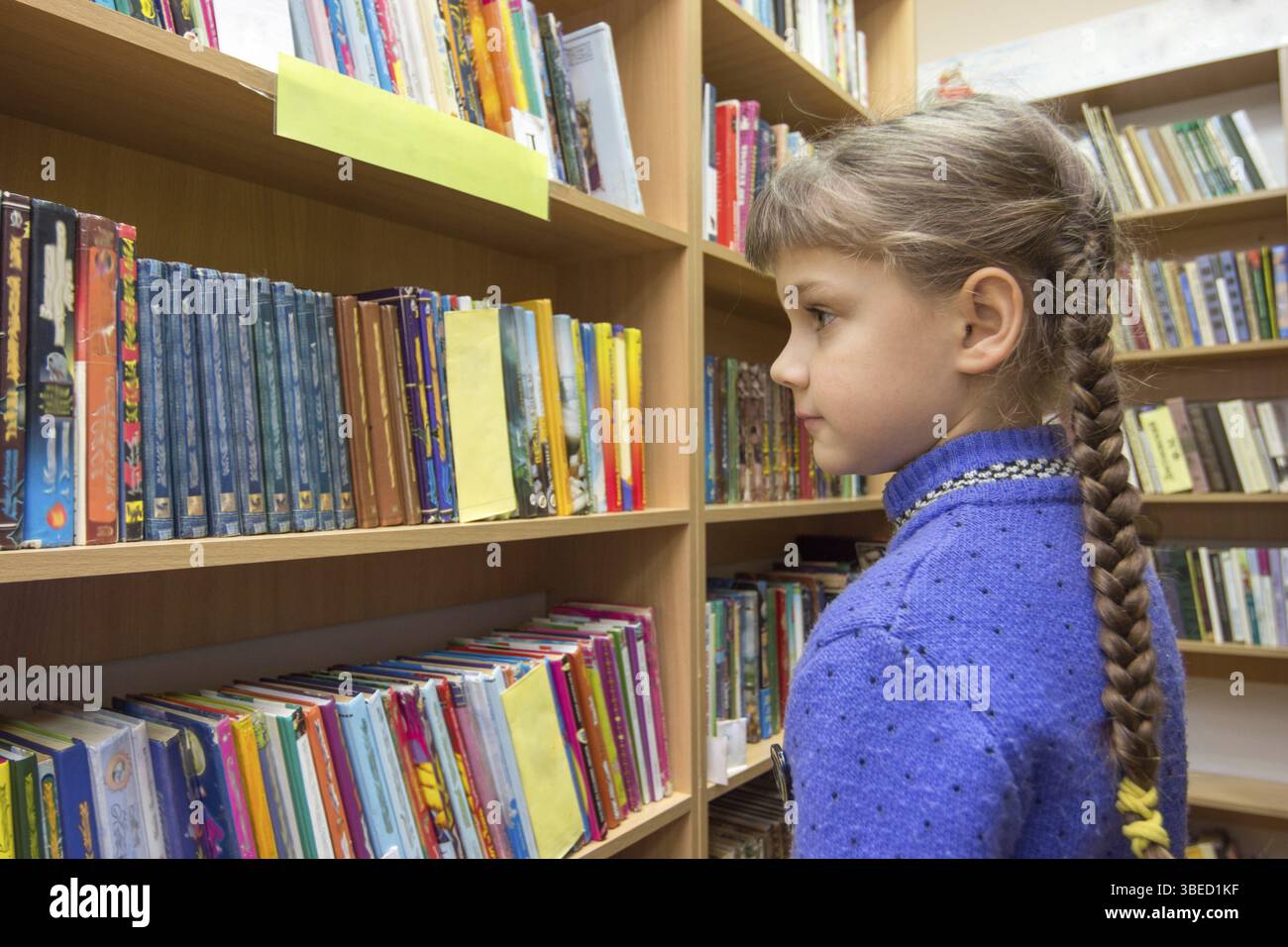 The girl chooses books in the library Stock Photo - Alamy