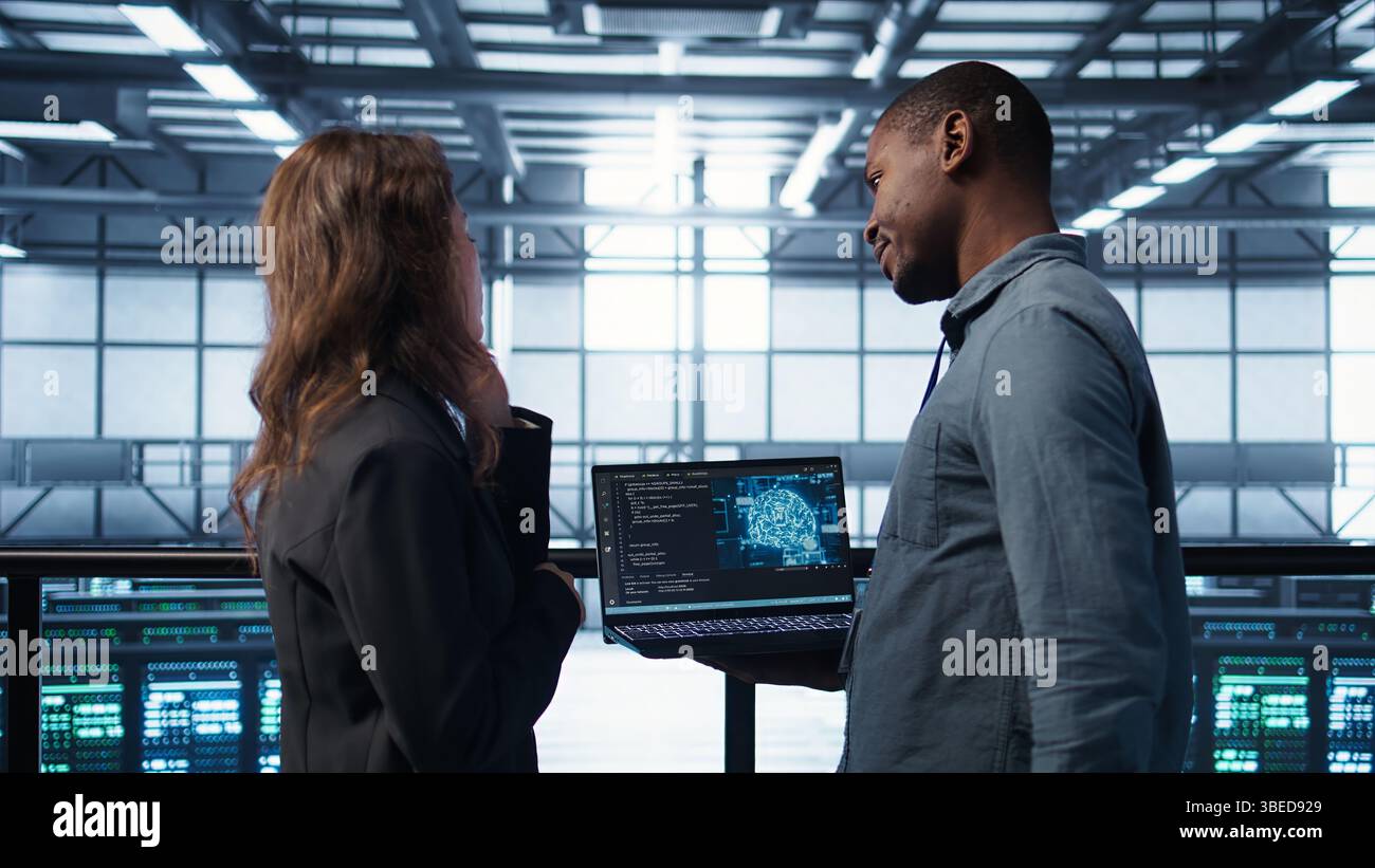 Software developers in data center using laptop, employing AI machine learning models. Workers ...