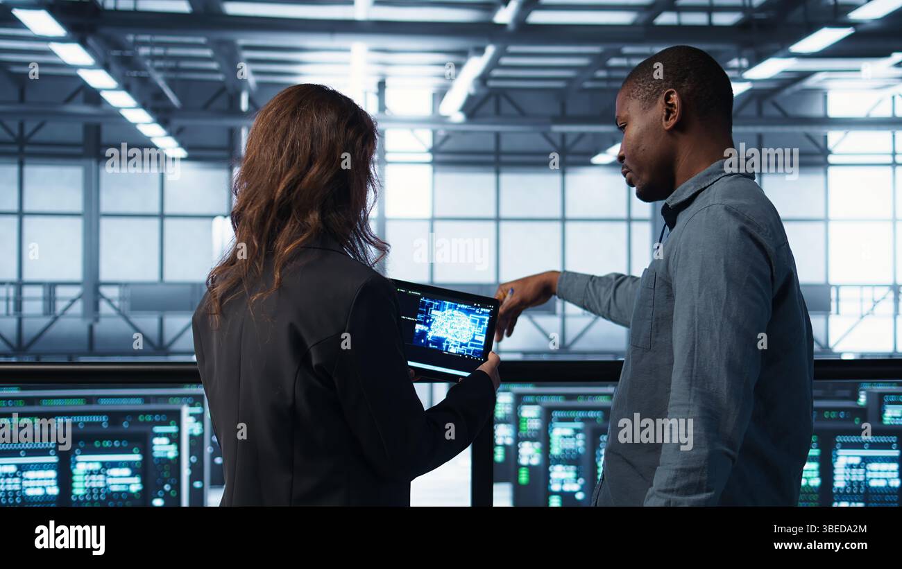 Data center technicians deploying AI driven management tools using tablet. Server farm coworkers ...