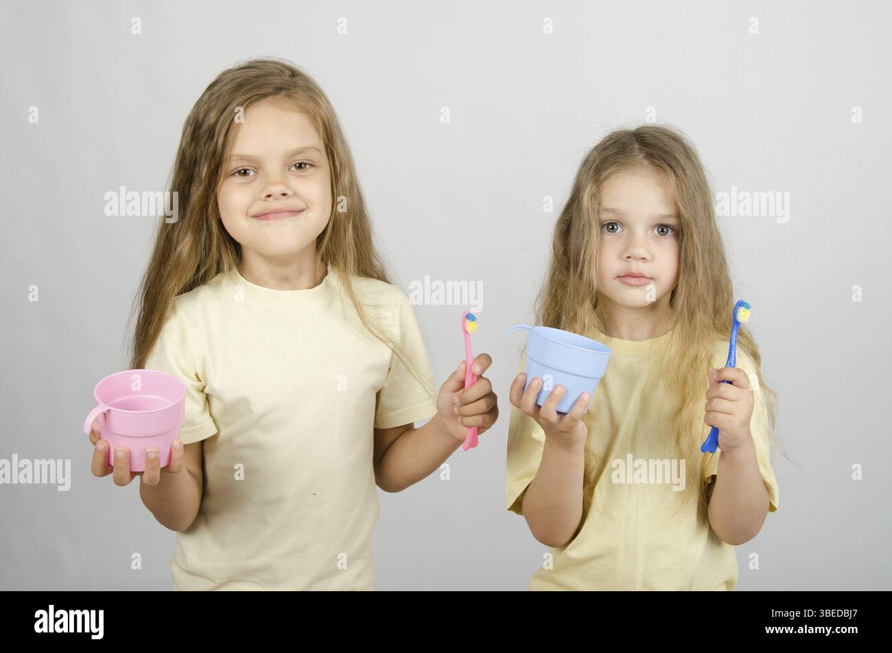 Two girls of four and six years of brushing their teeth toothbrushes ...