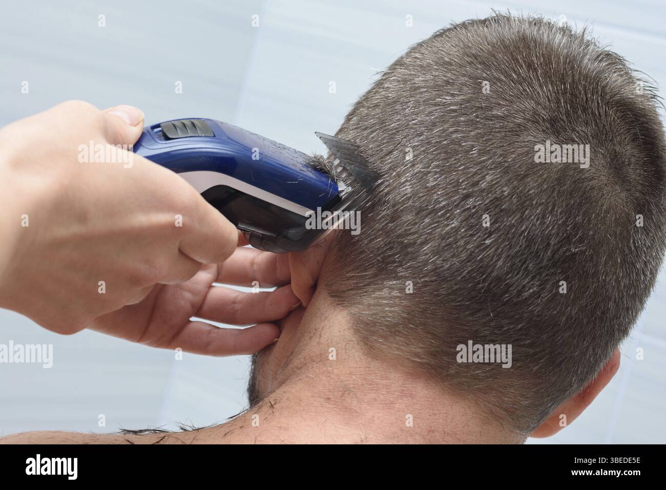 Hairdresser smoothes and shortens the hair on the man's head in the ...