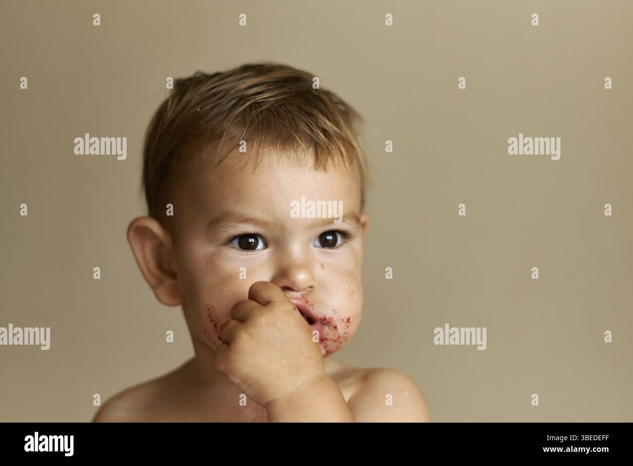 Baby girl eating berries, messy face, one year old. Portrait close up ...