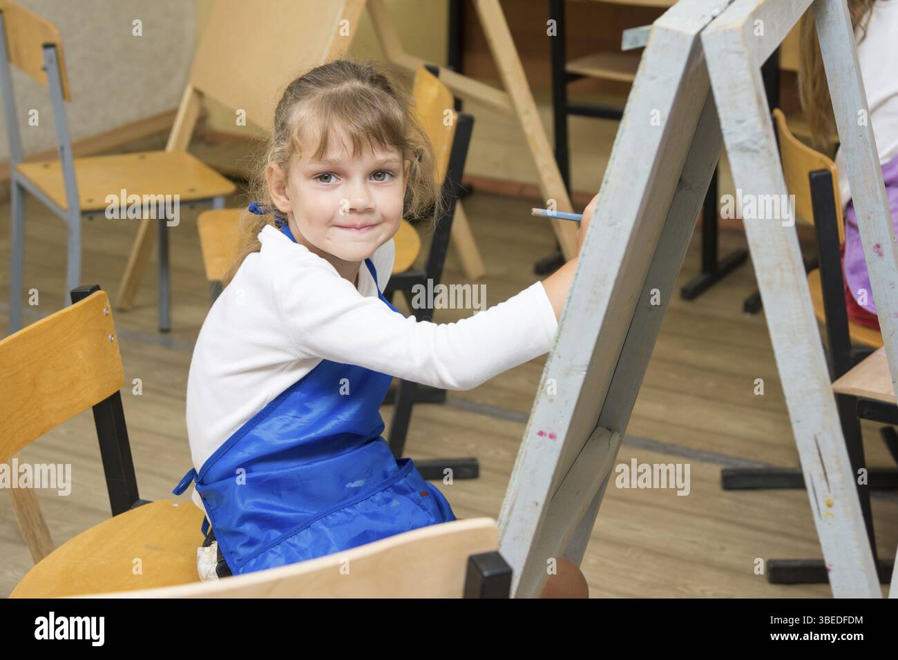 Girl draws pencil on an easel to draw a lesson and looked into the ...