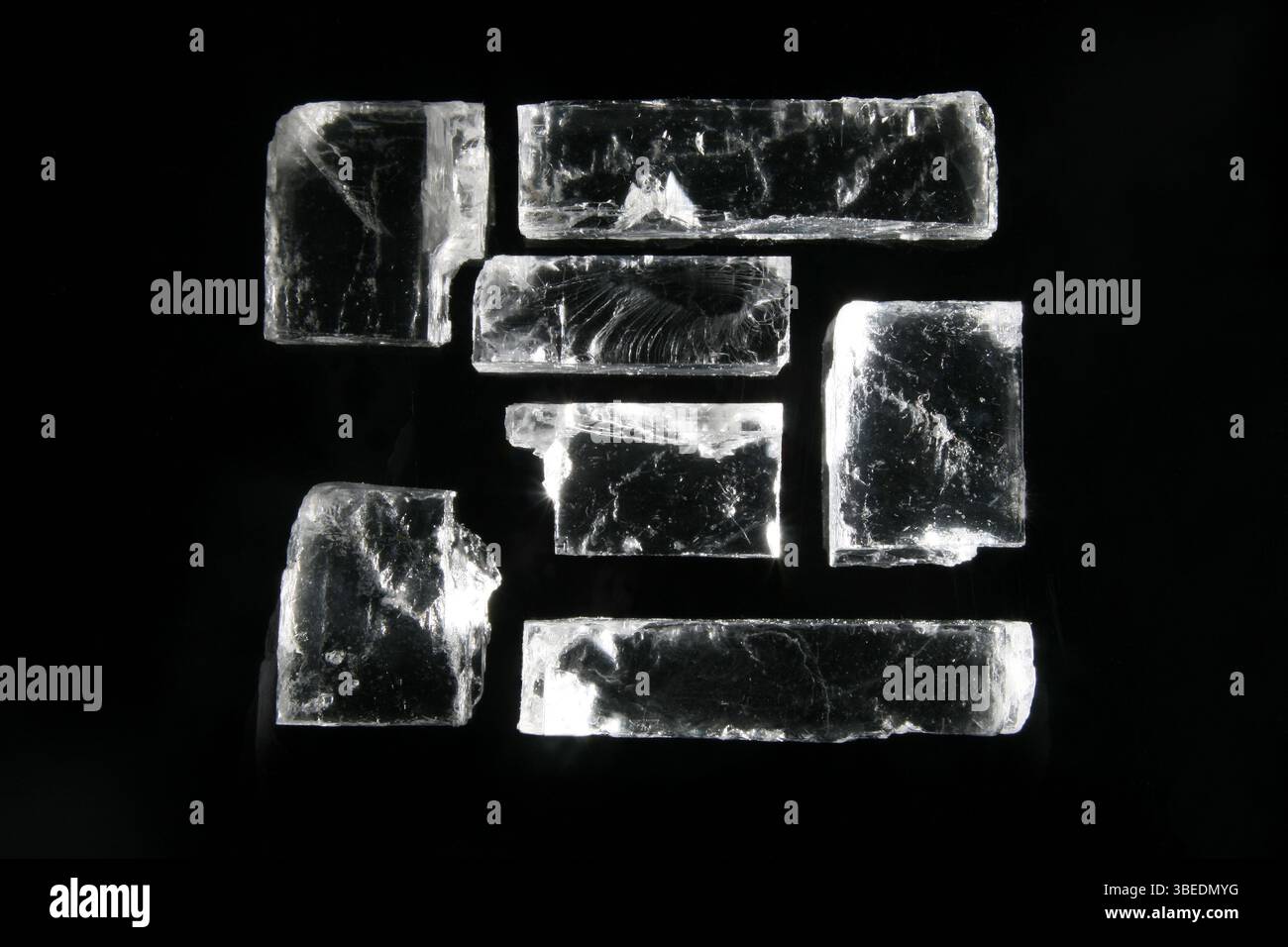 Halite crystal cleaved into smaller cubic crystals against a black ...