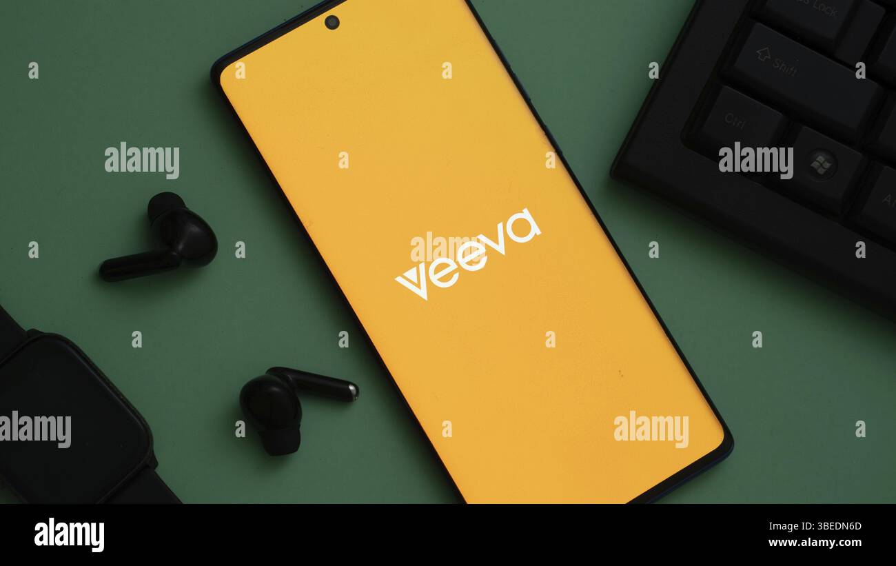 Veeva logo displayed on a smartphone with an orange screen and tech setup Stock Photo - Alamy