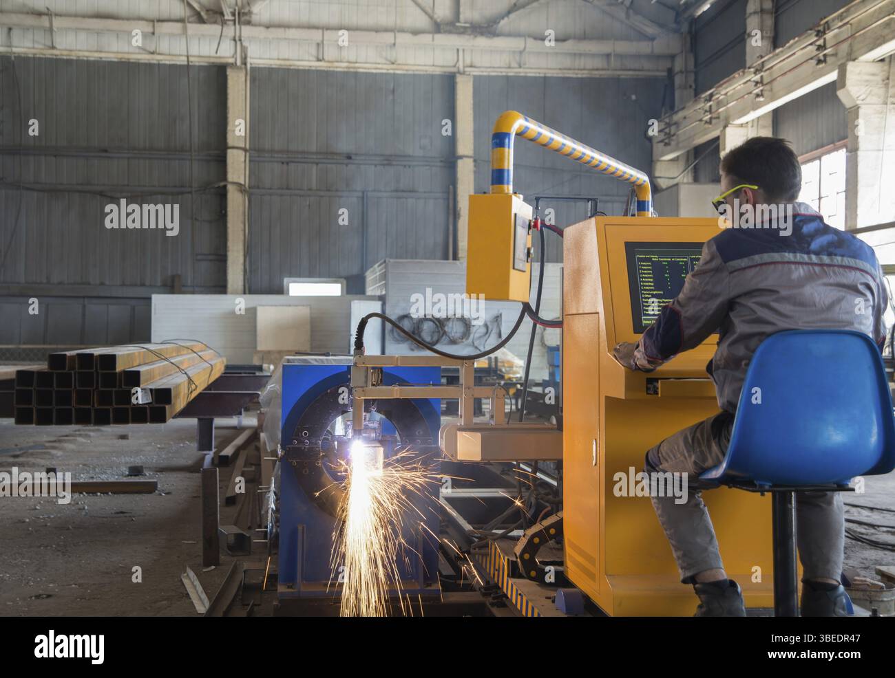 Worker sits behind a remote control gas welding machine. pipe cutting ...