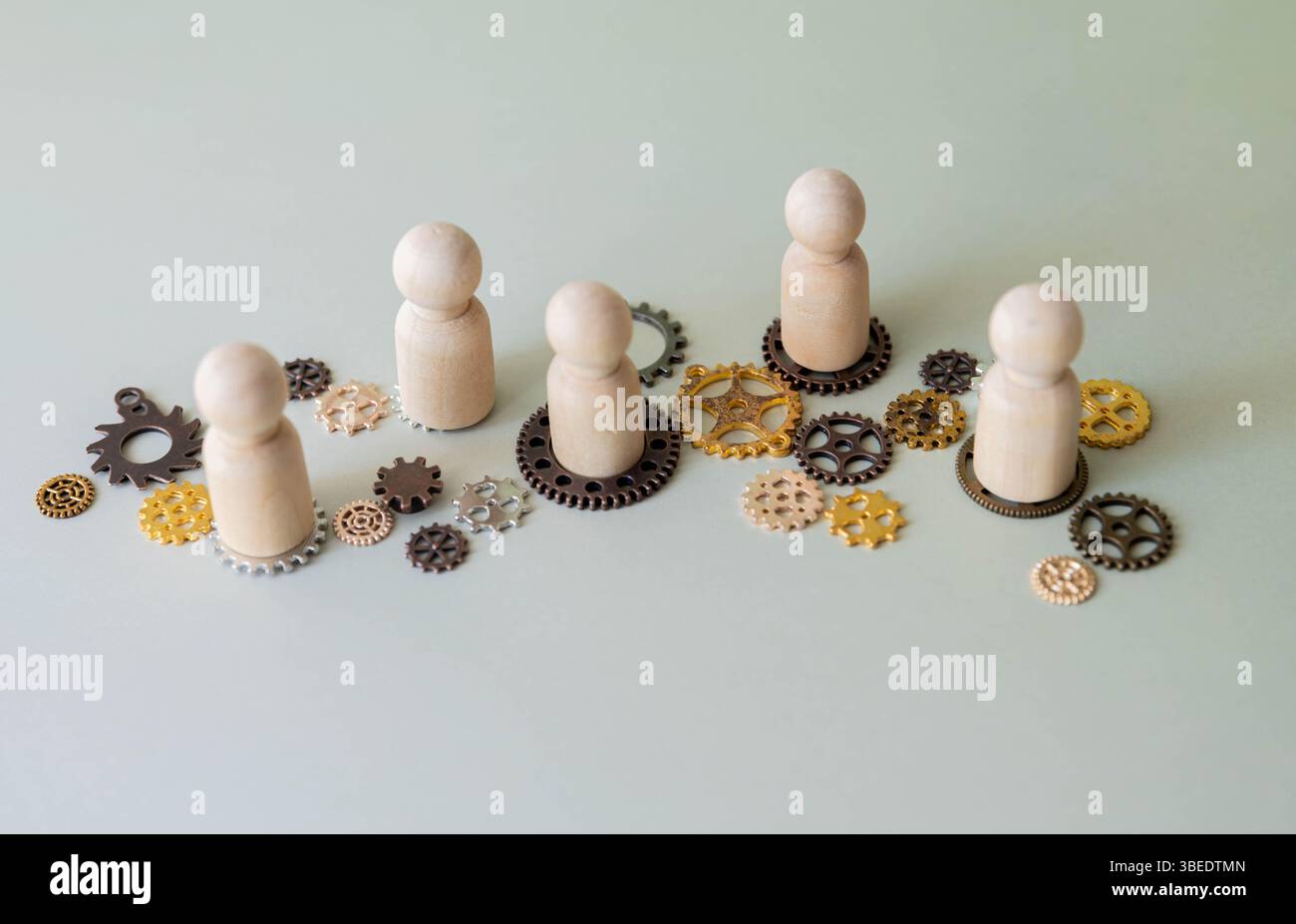 A conceptual image with wooden figures standing on interconnected gears ...