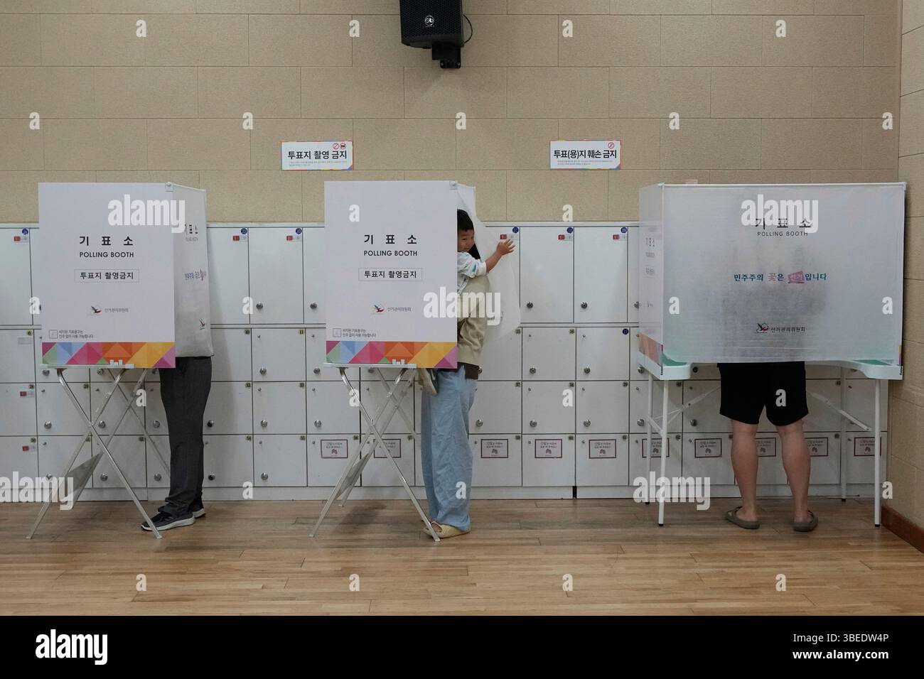 A boy waits for his mother casting her early vote for the June 3 ...
